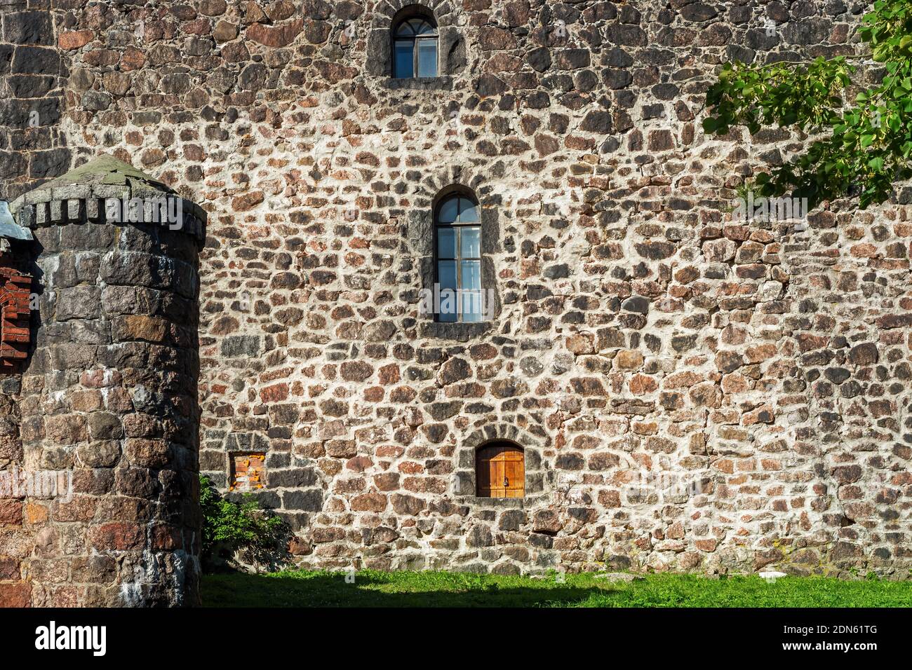 The fortified stone wall of the old castle with small windows and a ...