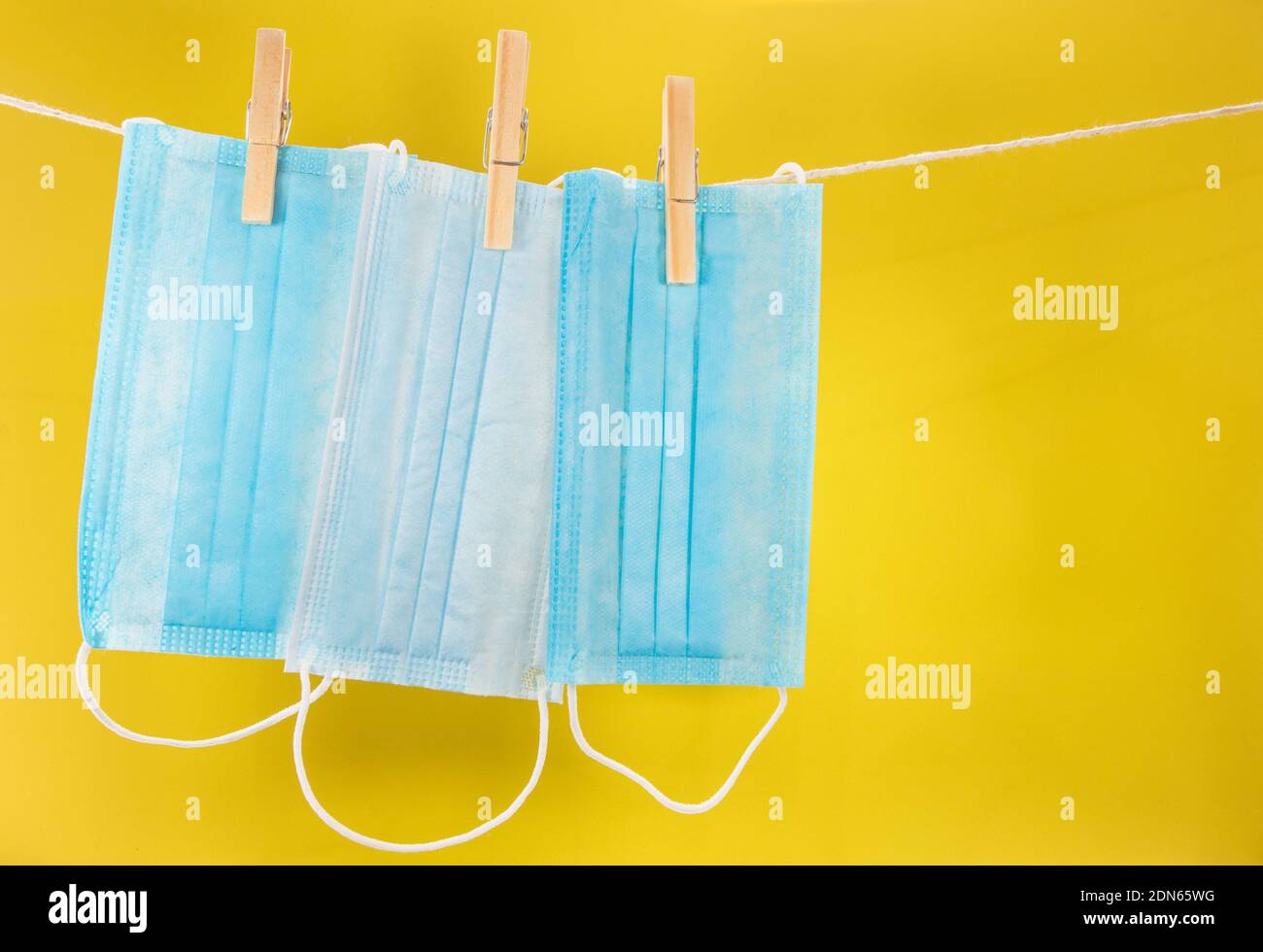 A closeup shot of surgical single use mask hanged on rope by a laundry ...