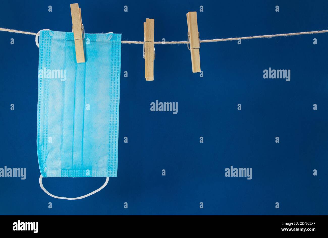 A closeup shot of a surgical single use mask hanged on rope by a ...