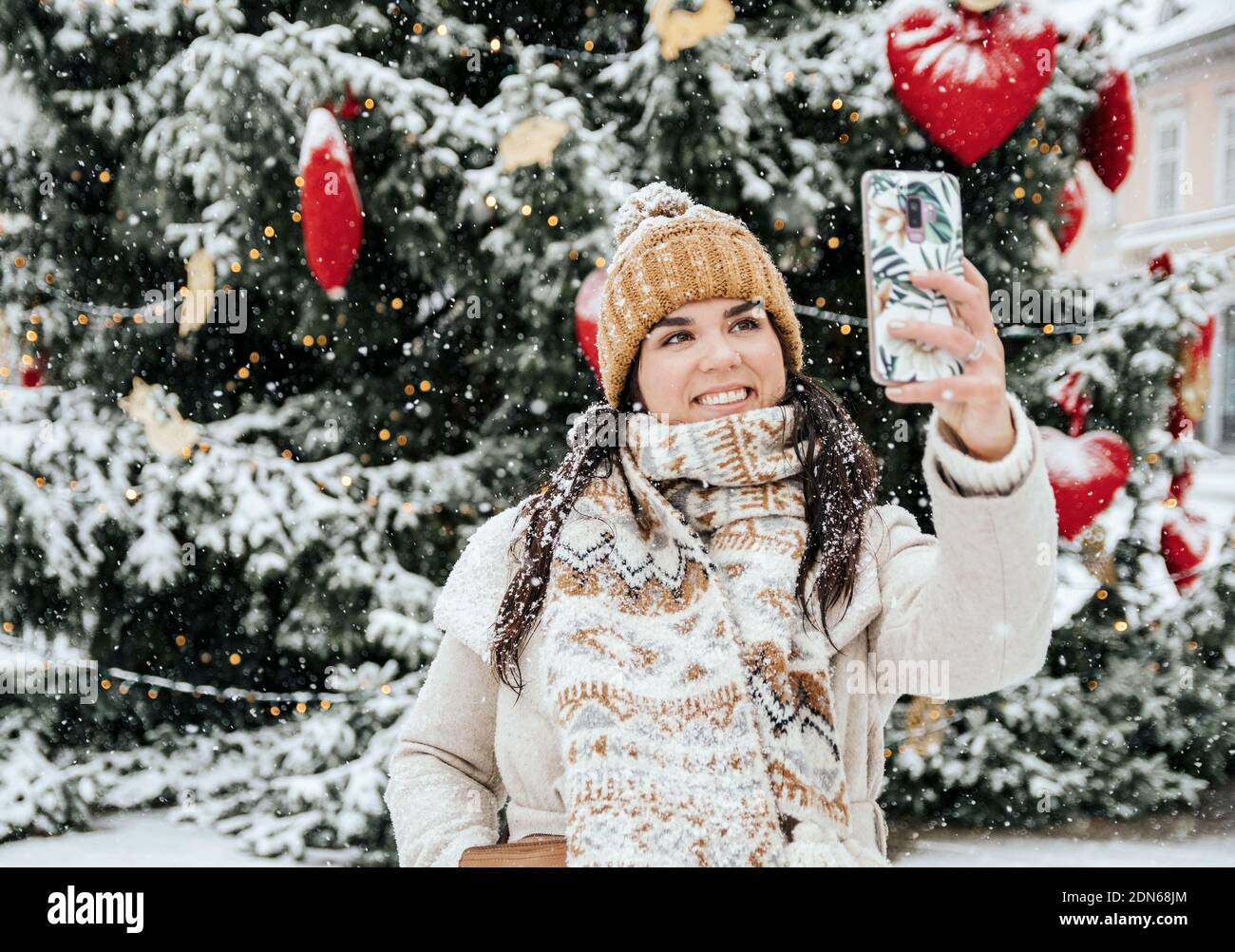A happy Caucasian woman doing a selfie near a Christmas tree Stock ...