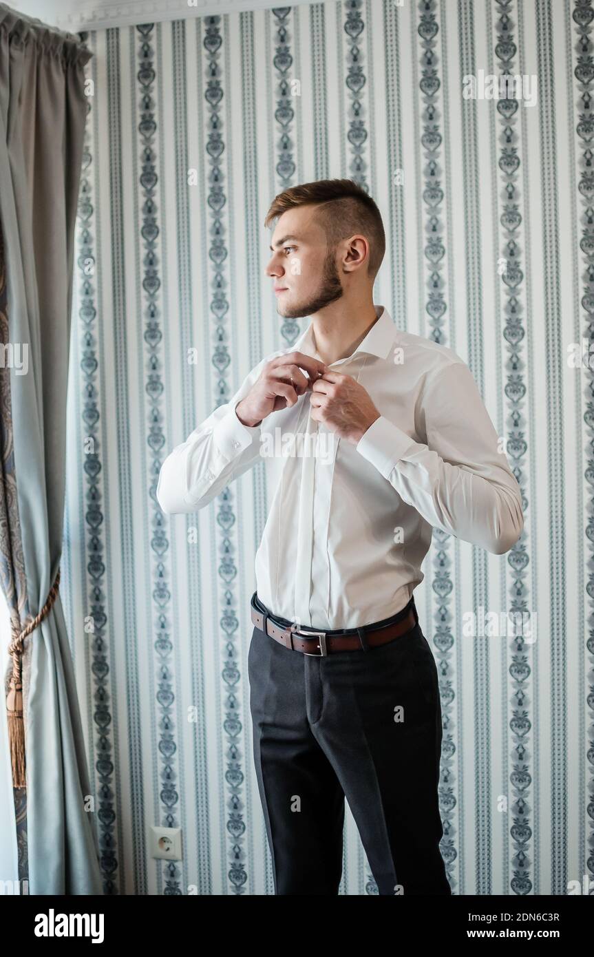Groom's morning. The groom buttons his shirt Stock Photo - Alamy