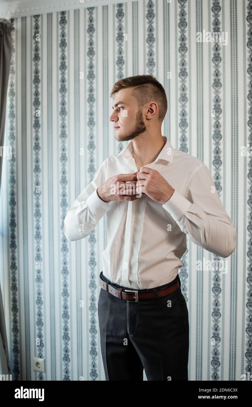 Groom's morning. The groom buttons his shirt Stock Photo - Alamy