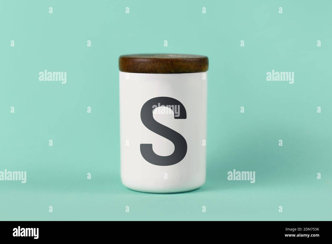 White salt shaker with wooden lid and letter 'S' on green background ...