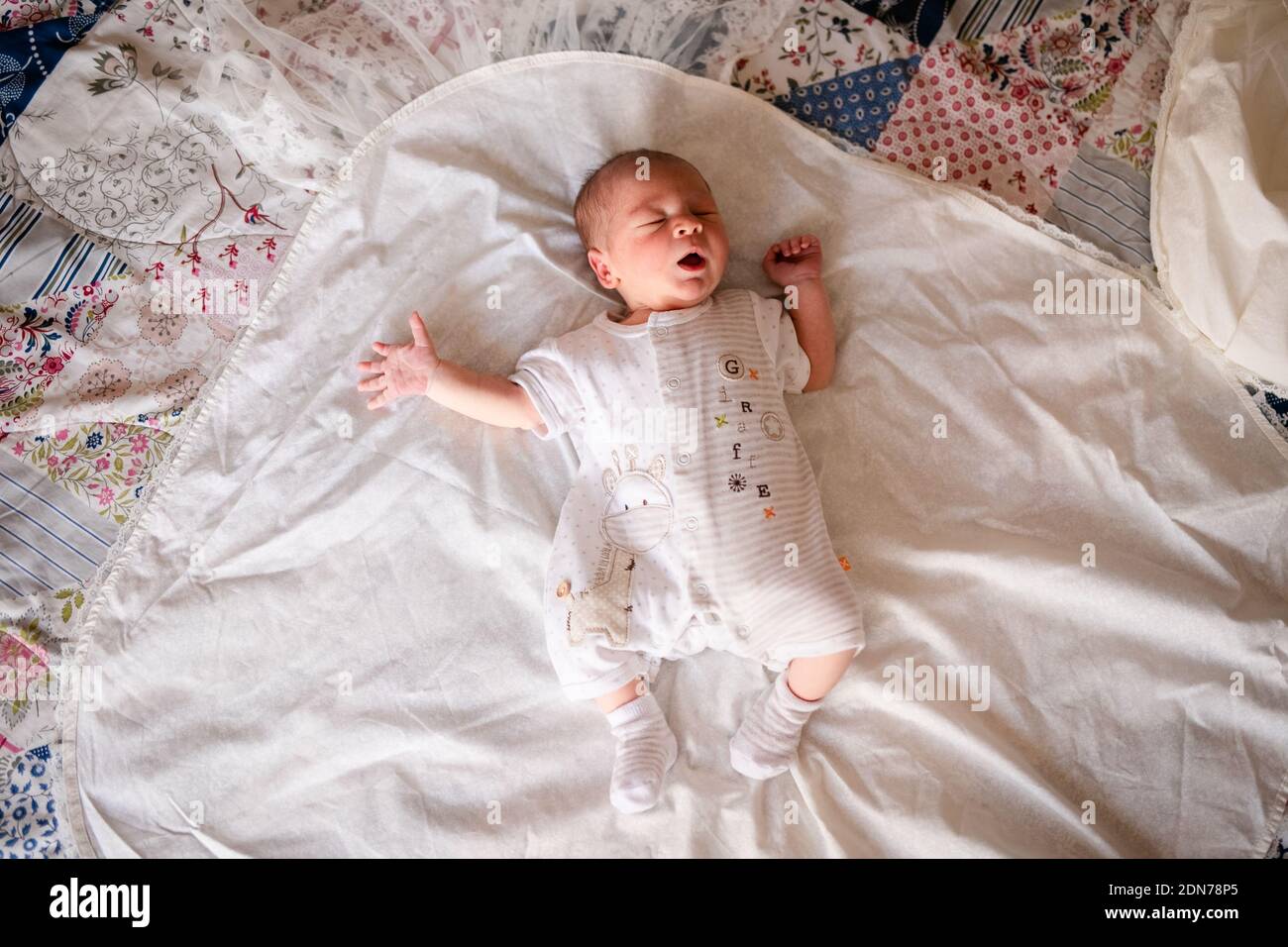 Newborn baby boy in bed. New born child in white bodykit lying in light ...