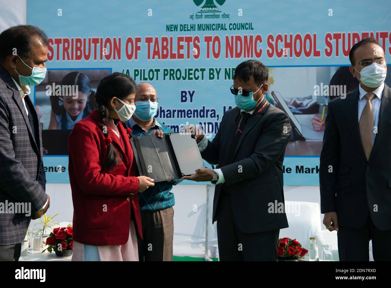 Chairman Shri Dharmendra handing over a tablet to a student during the ...