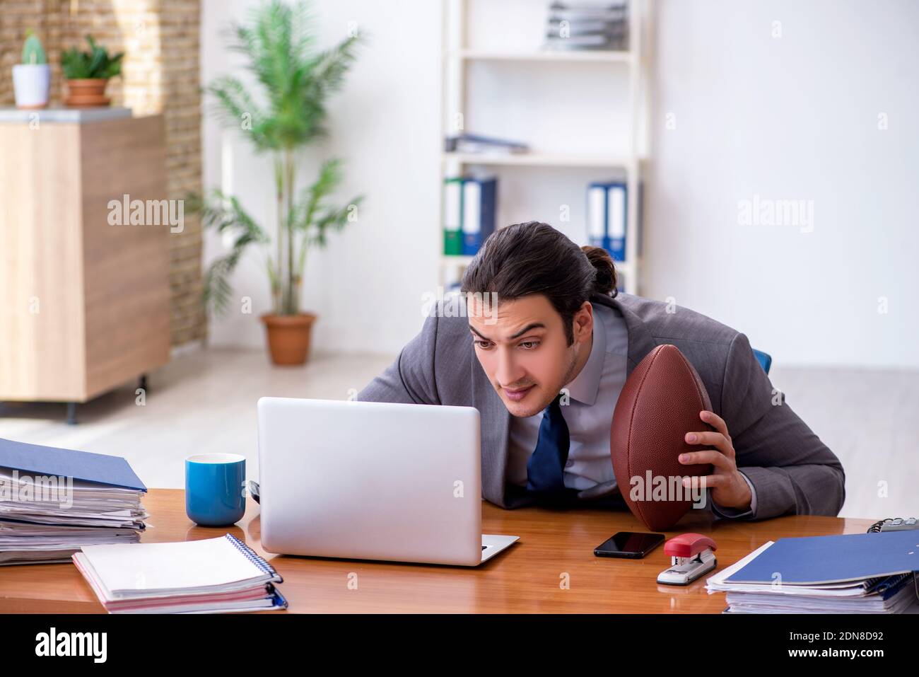 Male employee with rugby ball in the office Stock Photo - Alamy