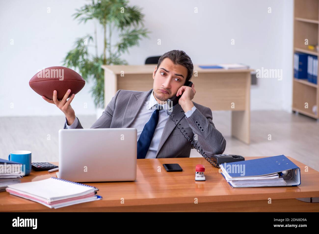 Male employee with rugby ball in the office Stock Photo - Alamy