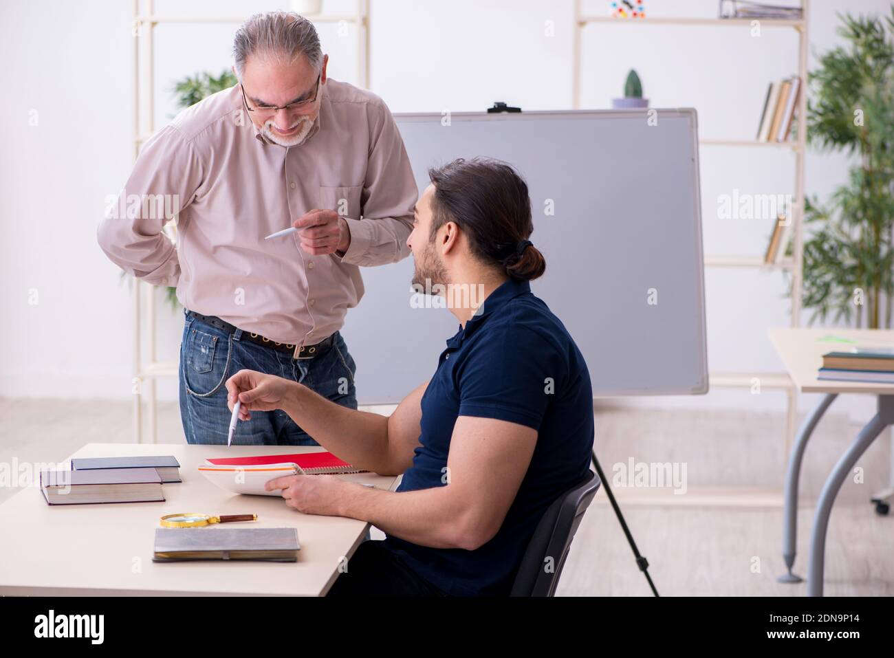 Old teacher and young student in the classroom Stock Photo - Alamy