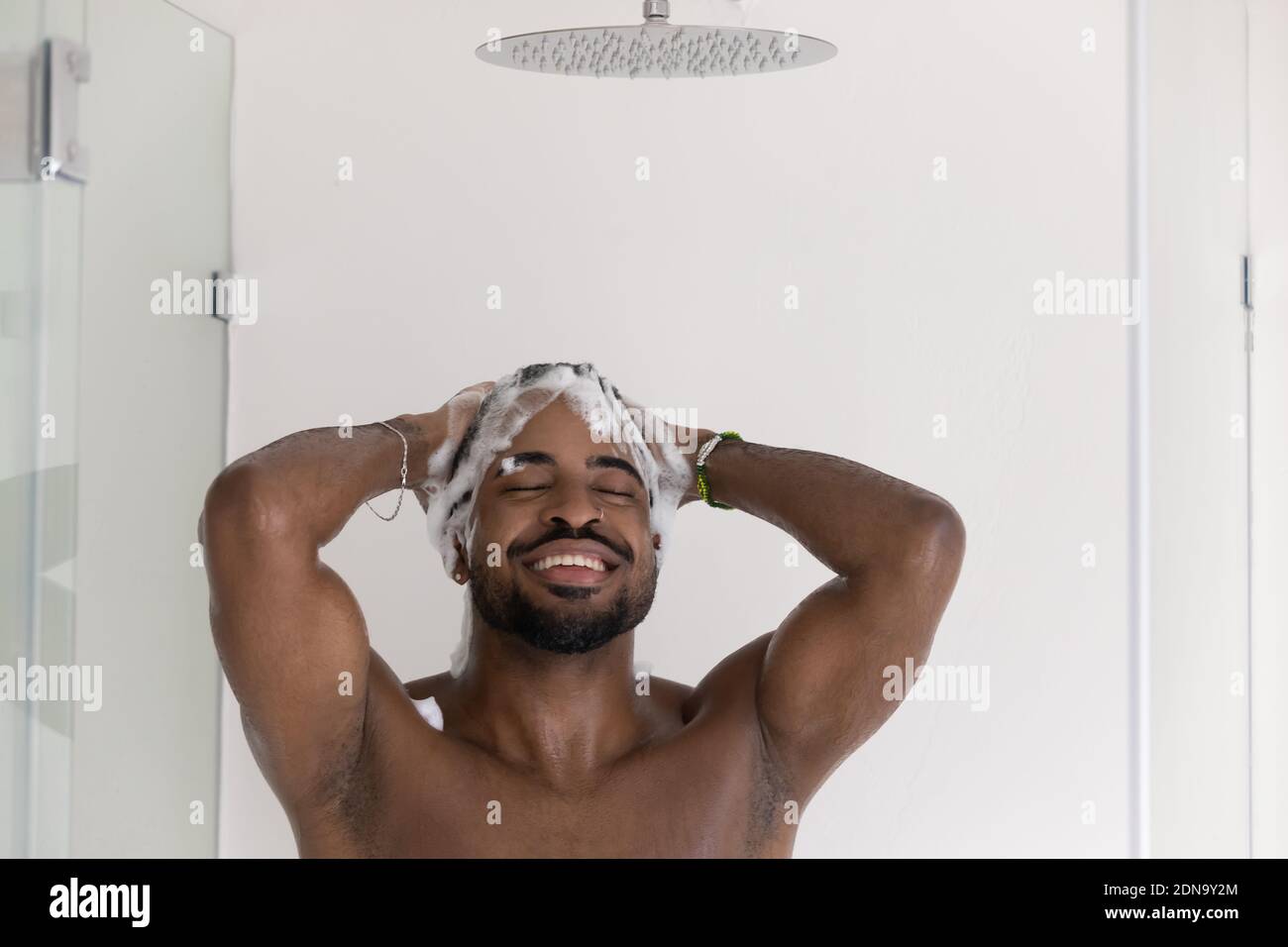 Smiling young african ethnic man washing head Stock Photo - Alamy