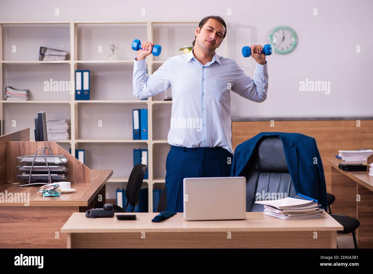 Young employee doing physical exercises at workplace Stock Photo - Alamy