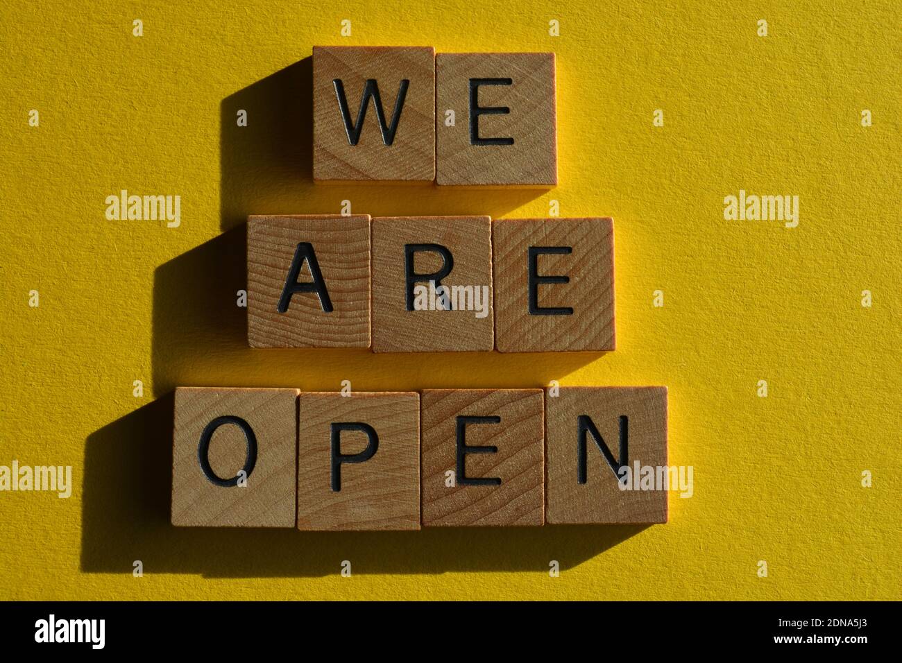 We Are Open, words in wooden alphabet letters isolated on bright yellow ...