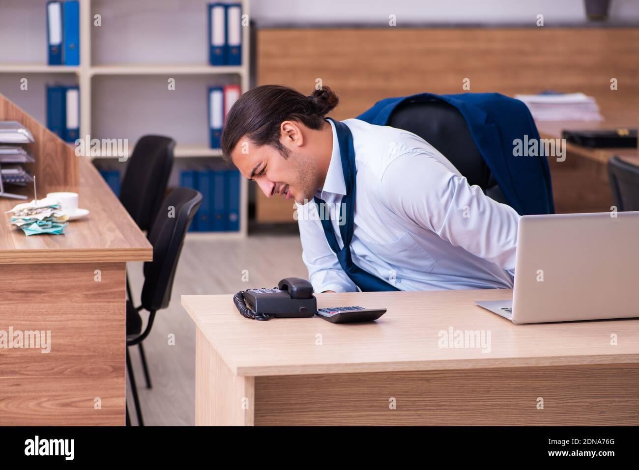 Young employee stretching at workplace Stock Photo - Alamy