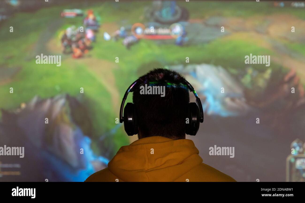 Gamer wearing headphones playing in front of a screen Stock Photo - Alamy
