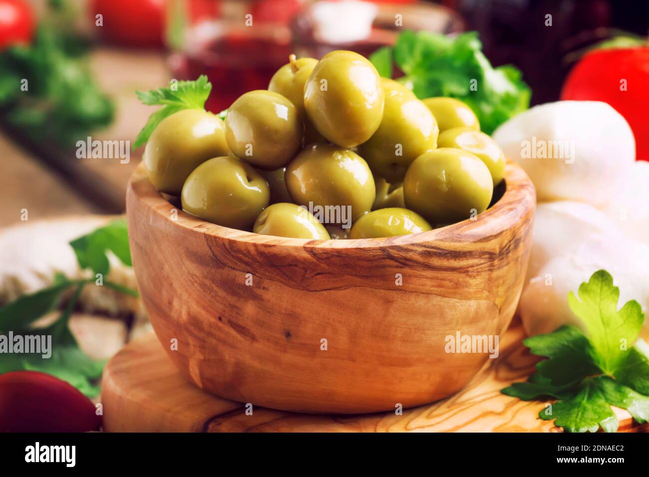 Salted Spanish green olives in wooden bowl and appetizers, rustic style ...