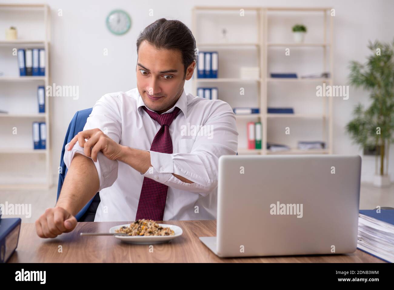 Hungry employee eating buckwheat during break Stock Photo - Alamy
