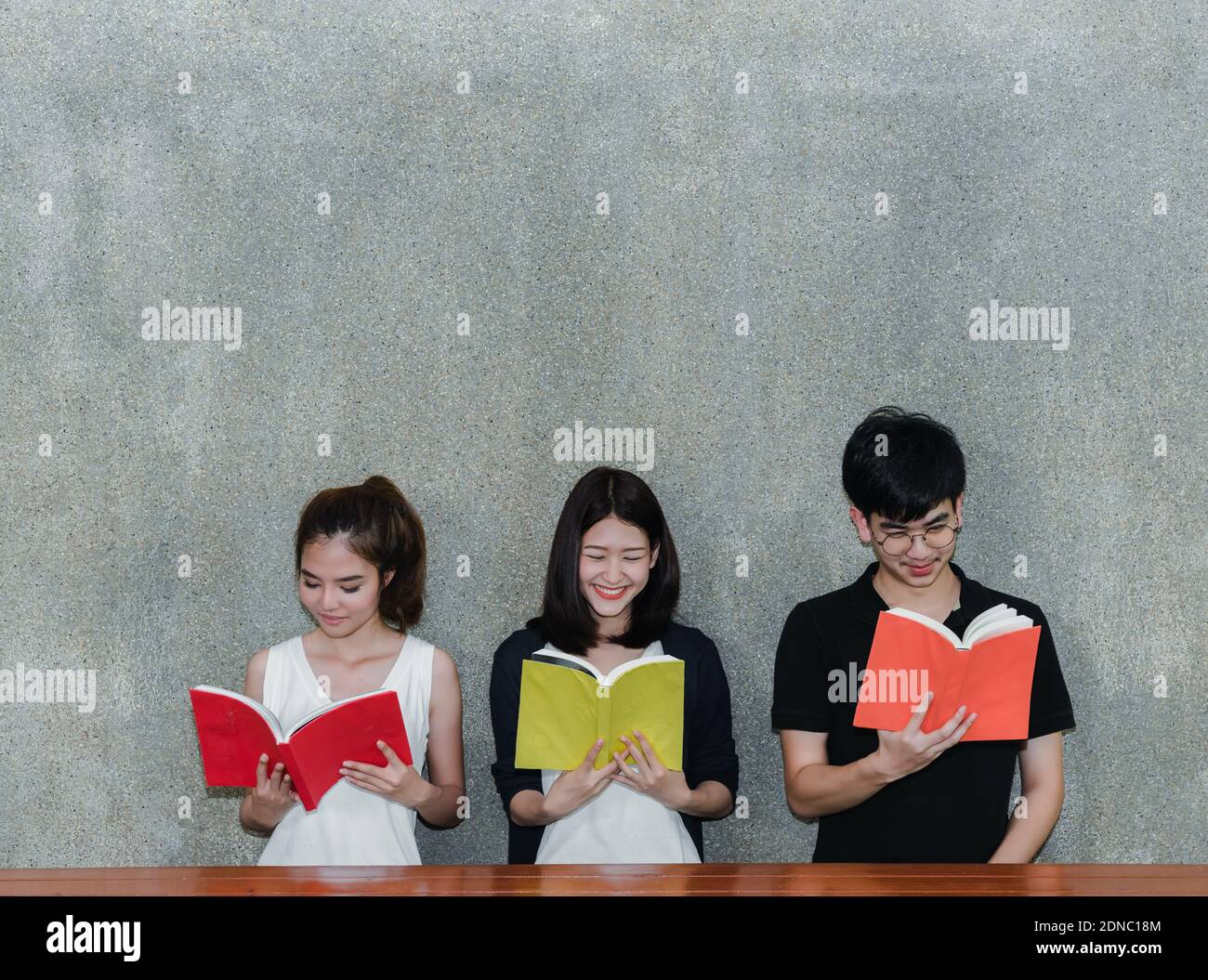 Friends Reading While Sitting By Table Against Wall In Classroom Stock ...