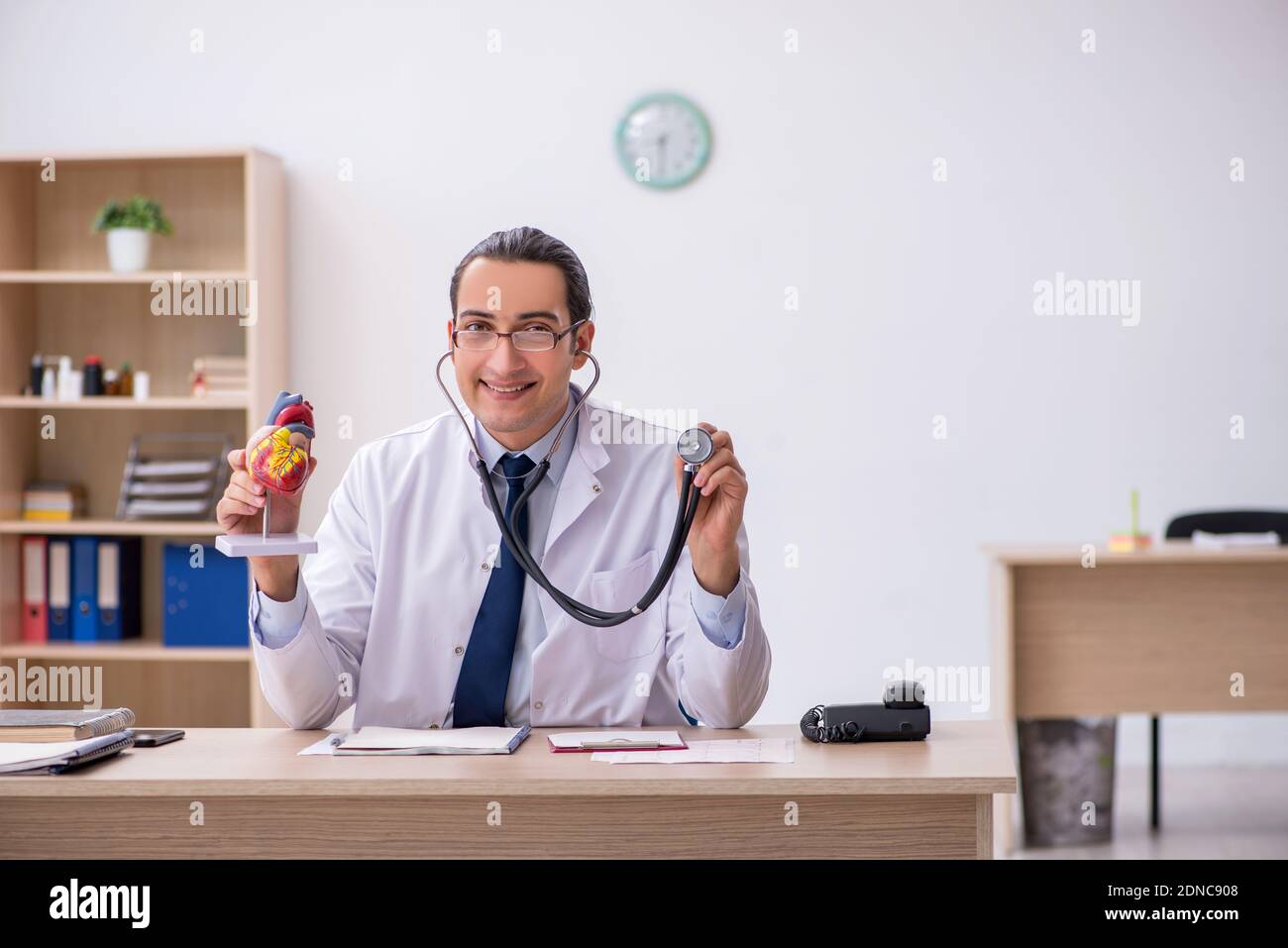 Young doctor cardiologist listening heart model with stethoscope Stock ...