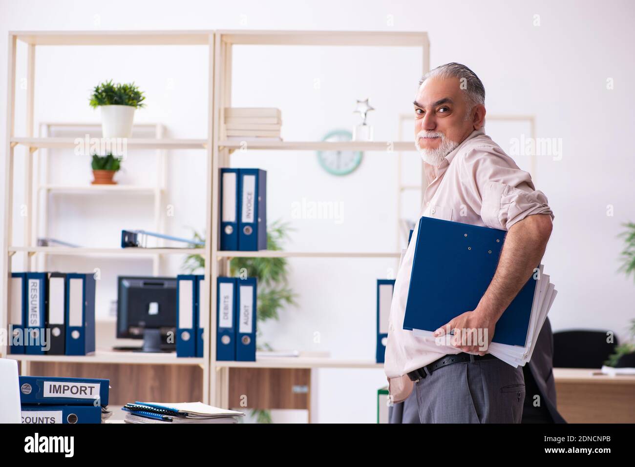 Senior male employee doing physical exercises at workplace Stock Photo ...