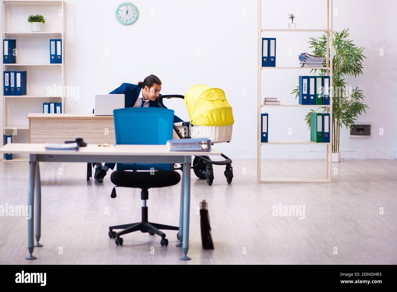 Young employee looking after kid at workplace Stock Photo - Alamy