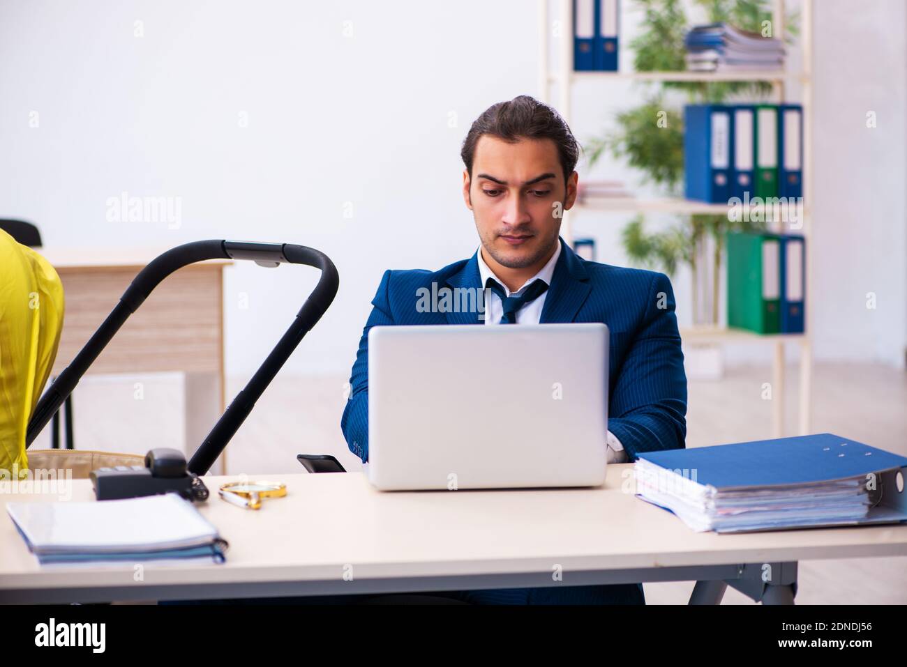 Young employee looking after kid at workplace Stock Photo - Alamy