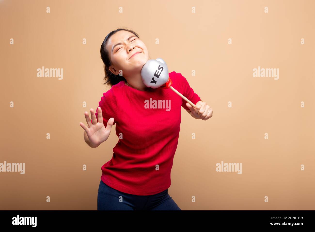 Woman Punching Herself With Prop Against Brown Background Stock Photo ...