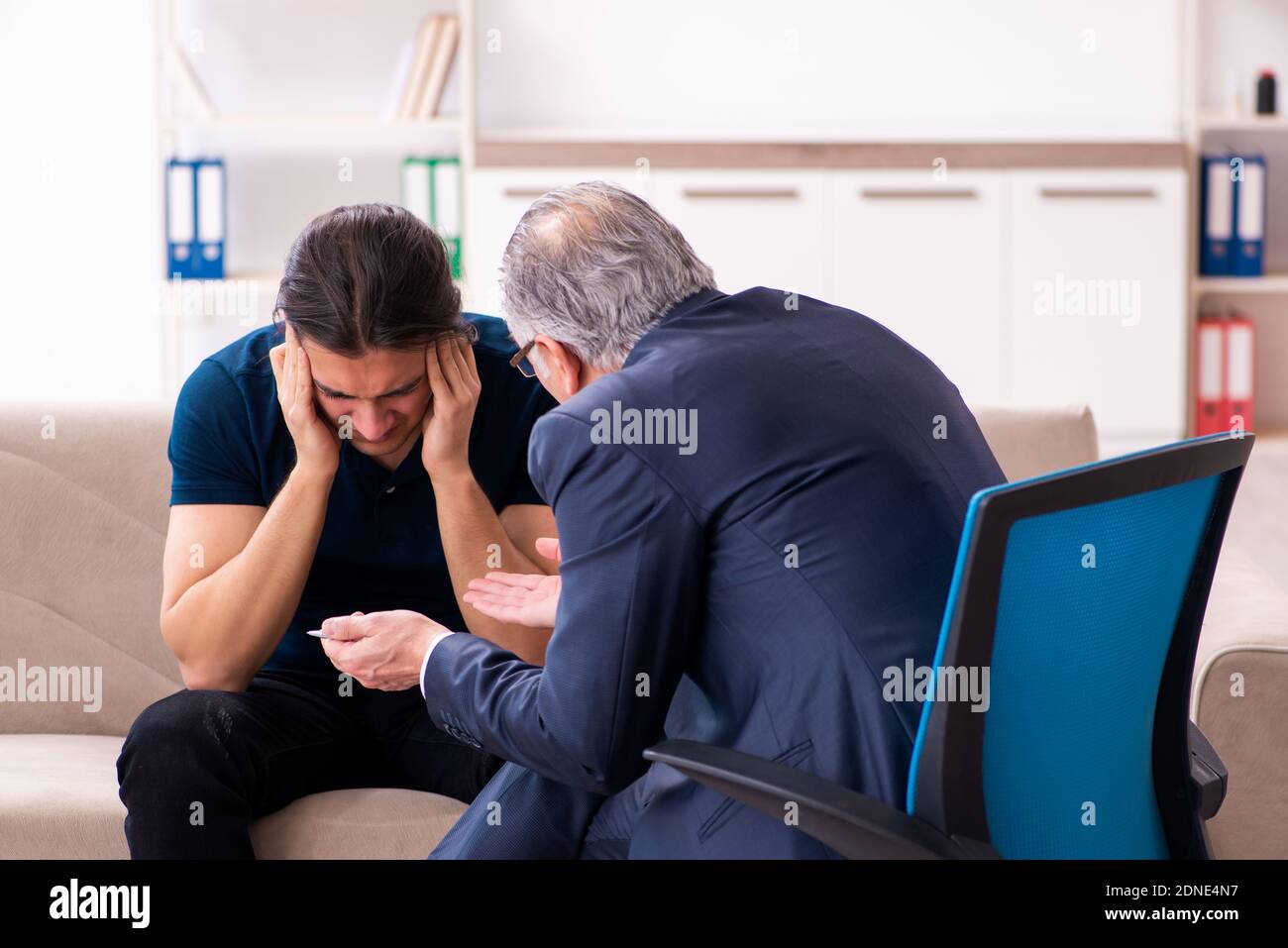 Young man visiting old psychologist Stock Photo - Alamy