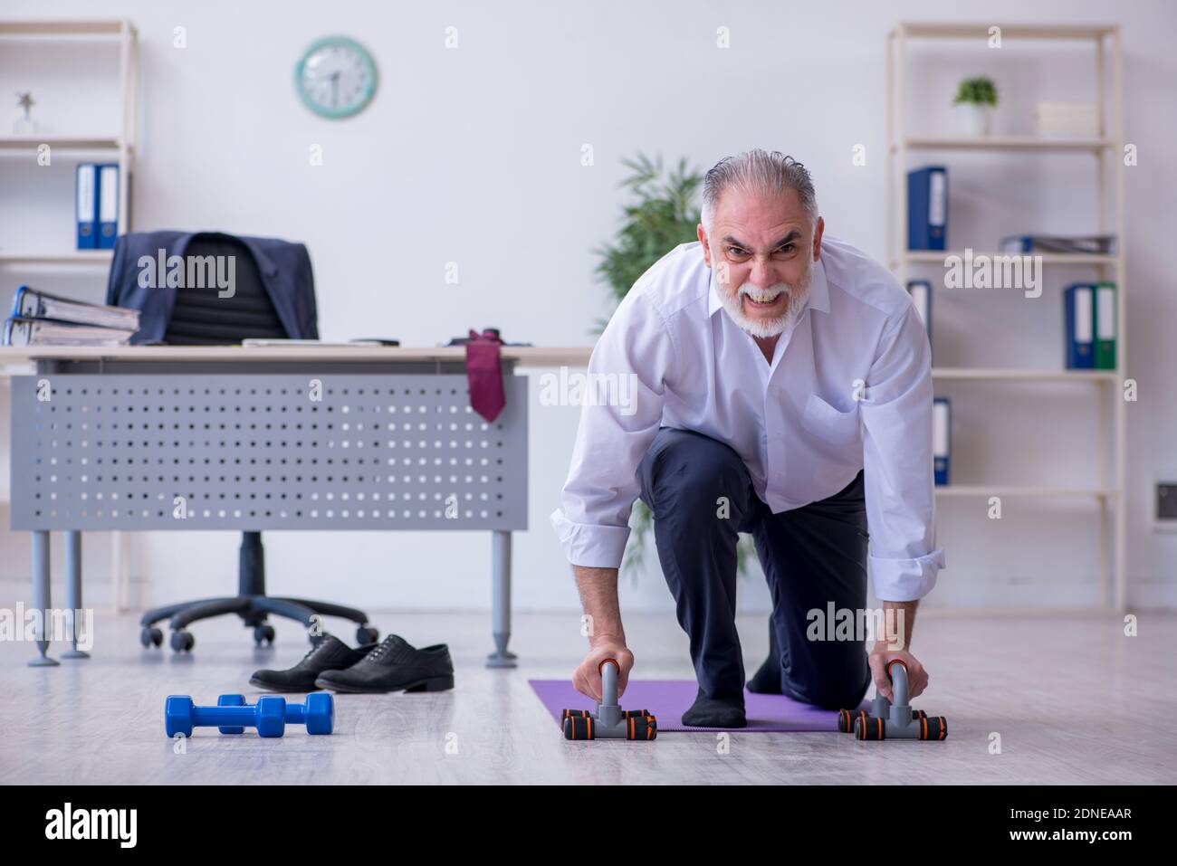 Aged employee doing physical exercises during break Stock Photo - Alamy