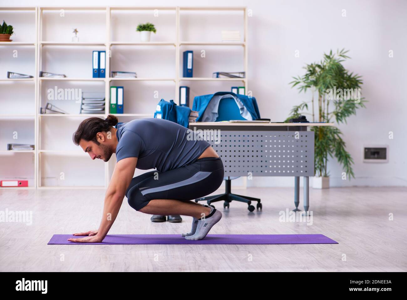 Young male employee doing sport exercises in the office Stock Photo - Alamy