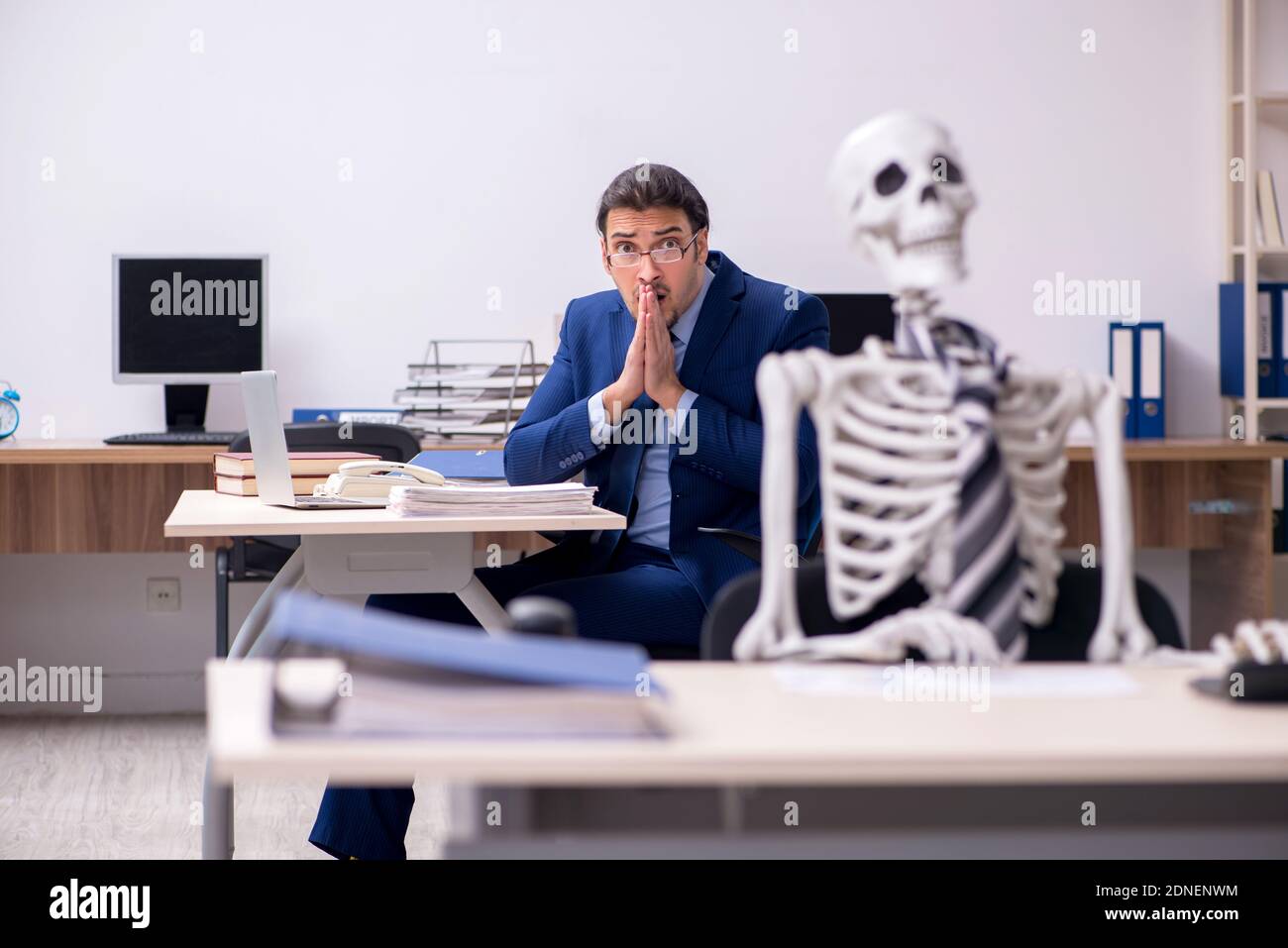 Young employee with skeletons in the office Stock Photo - Alamy