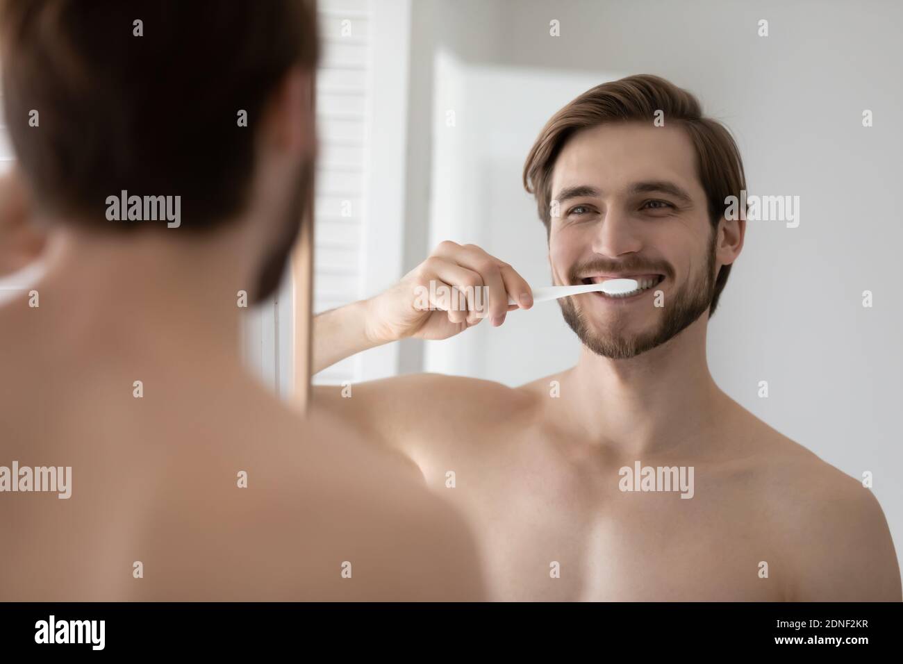 Happy young 30s bare european guy brushing teeth Stock Photo - Alamy