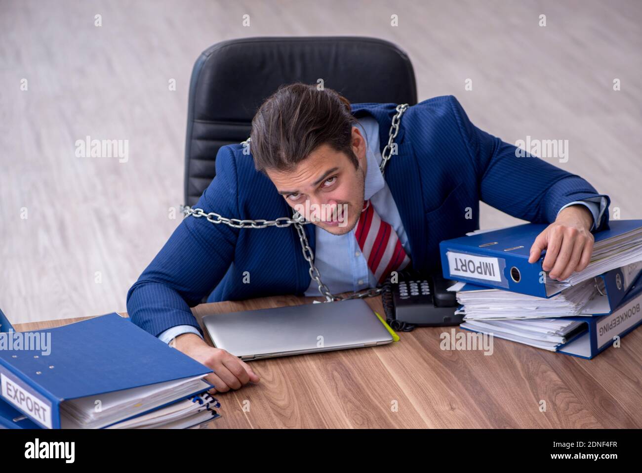 Chained employee unhappy with excessive work in the office Stock Photo ...
