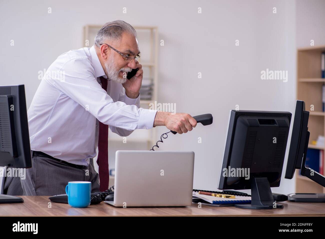 Old boss sitting at desktop in the office Stock Photo - Alamy