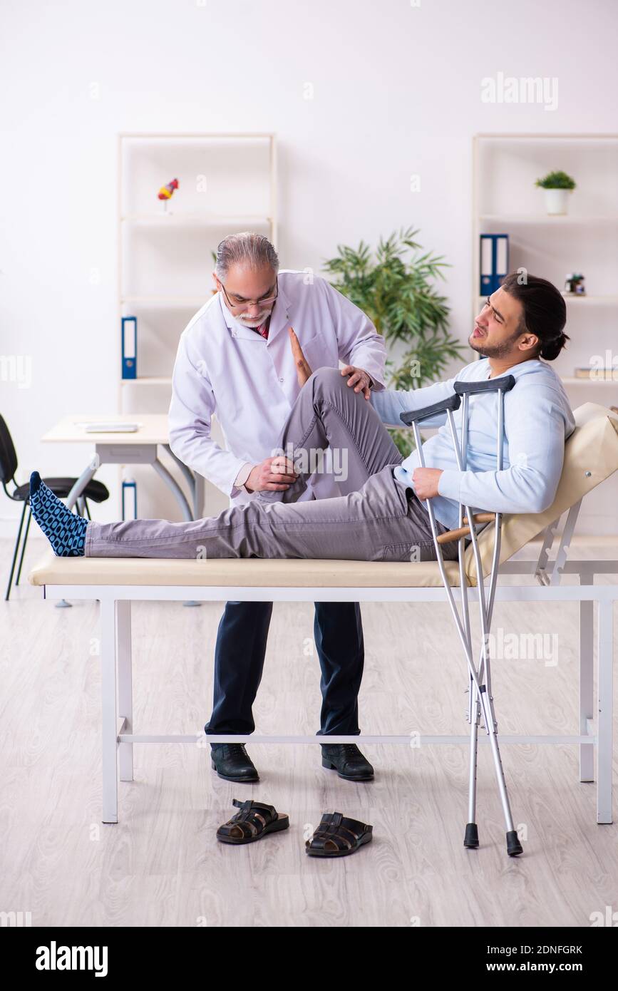 Leg injured man visiting old doctor osteopath Stock Photo - Alamy