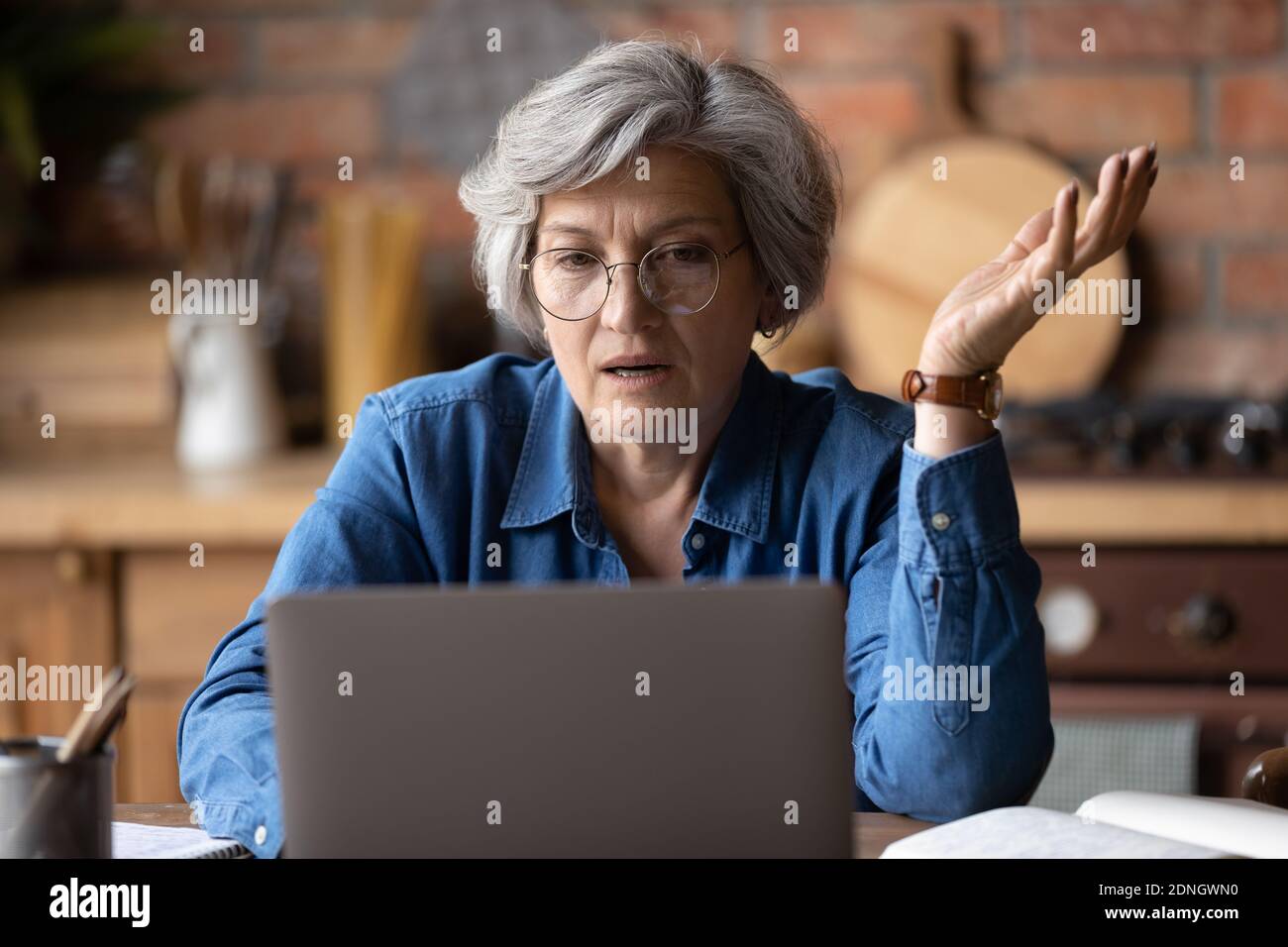Confused middle aged woman in glasses looking at computer screen Stock ...