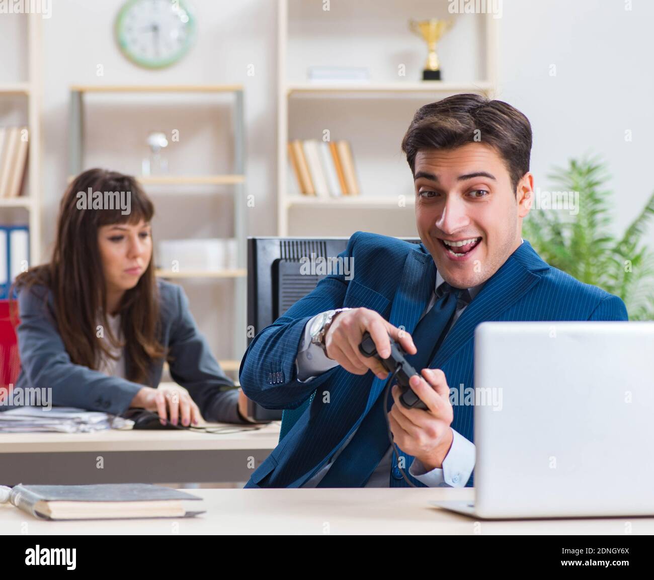 The man playing games in office while colleague is busy Stock Photo - Alamy
