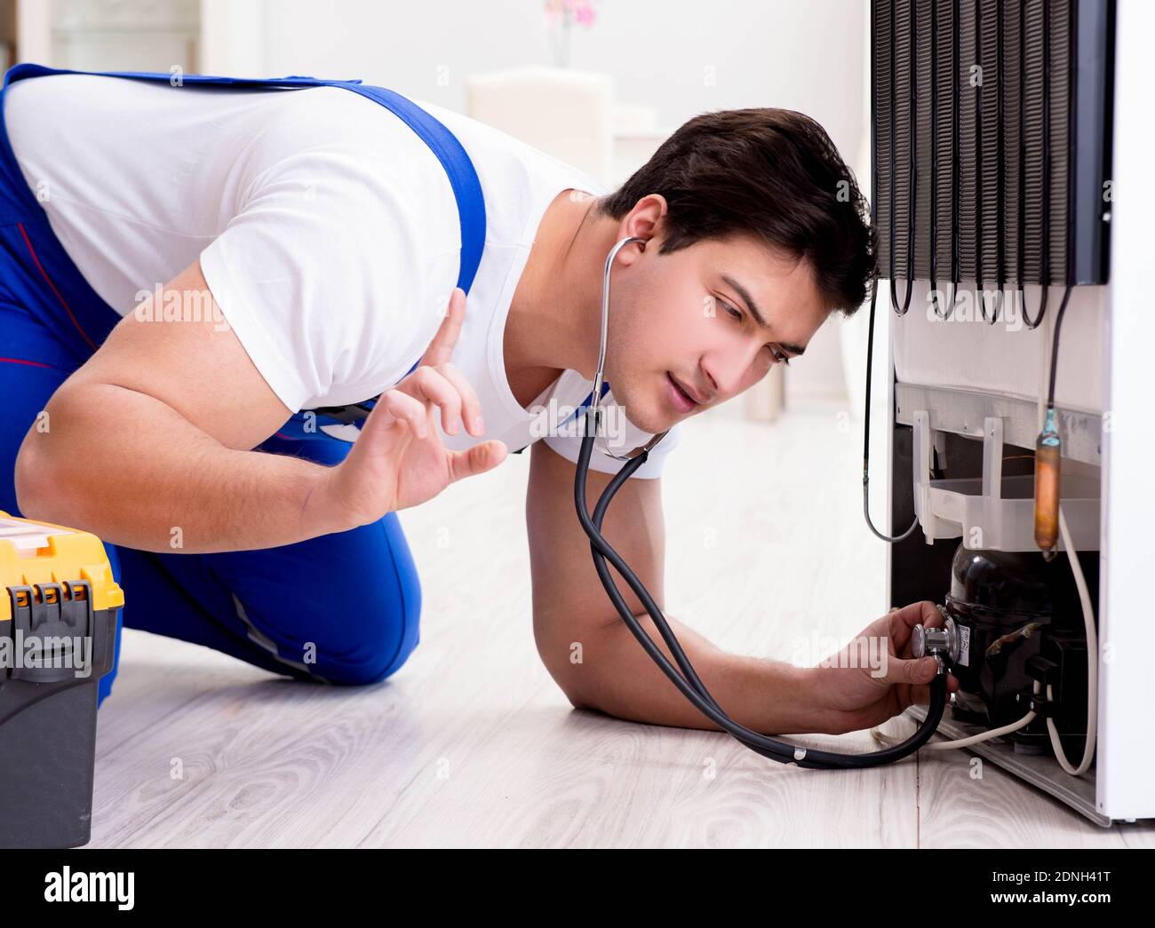 The repairman contractor repairing fridge in diy concept Stock Photo ...