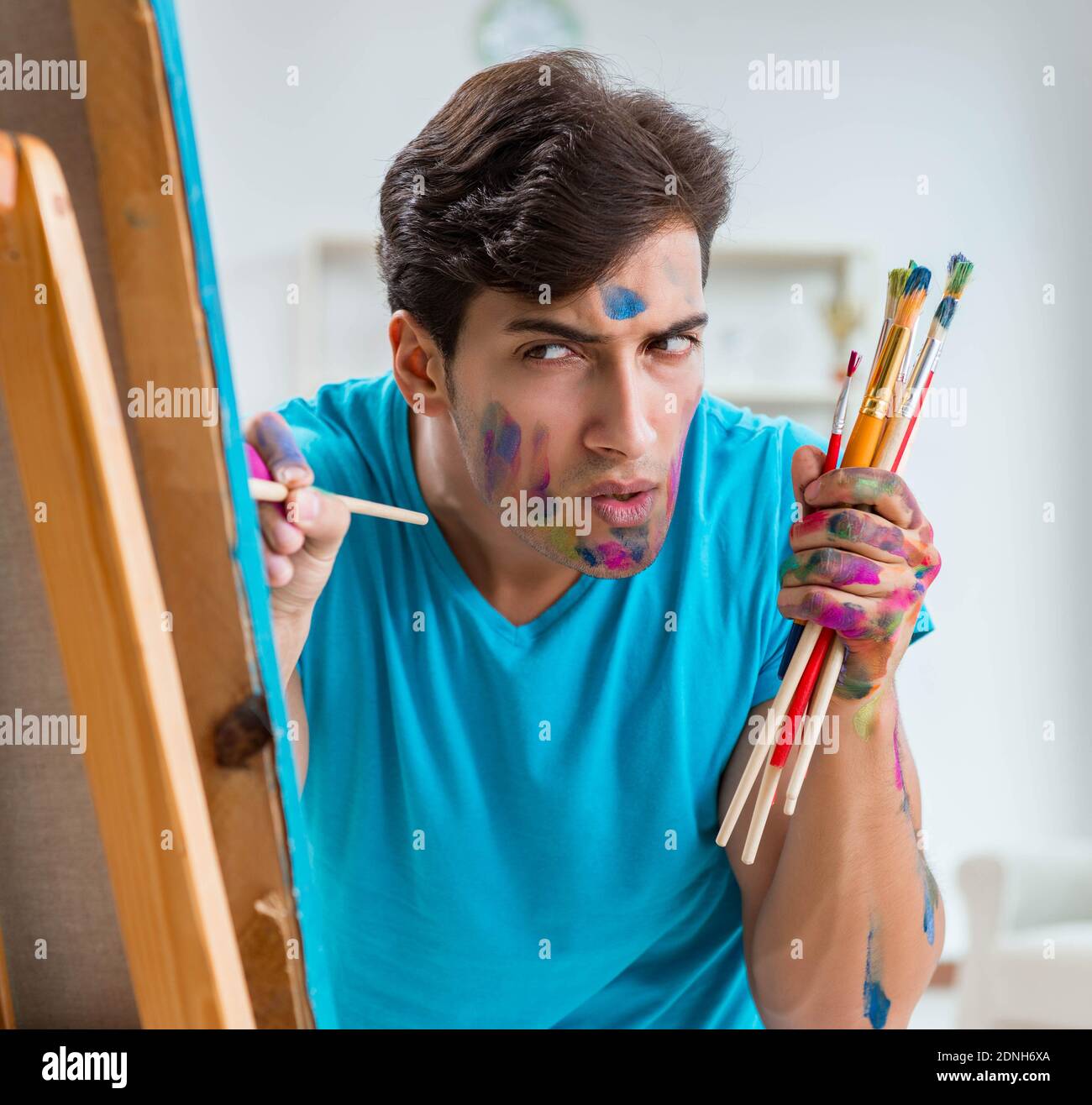 The young funny artist working on new painting in his studio Stock ...