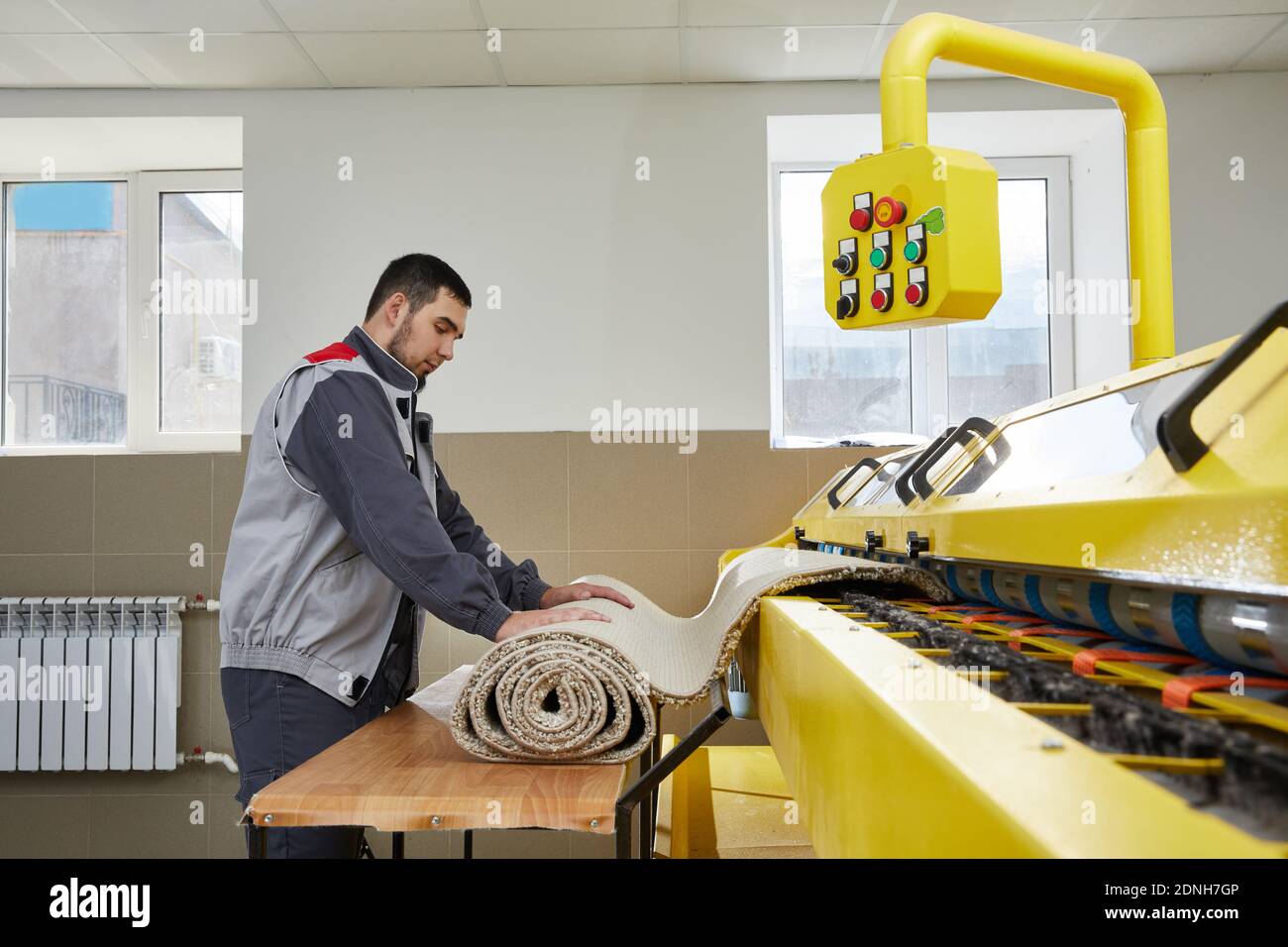 Man operating carpet automatic washing machine in professional laundry ...