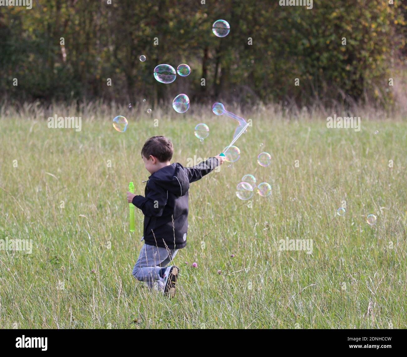 Playful Boy Blowing Bubbles While Running On Grass Stock Photo - Alamy