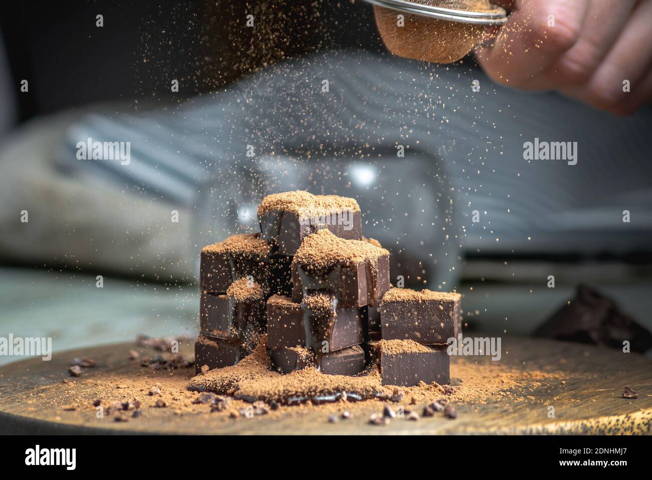 Hand is sprinkling cocoa powder on delicious appetizing cubes of bitter ...
