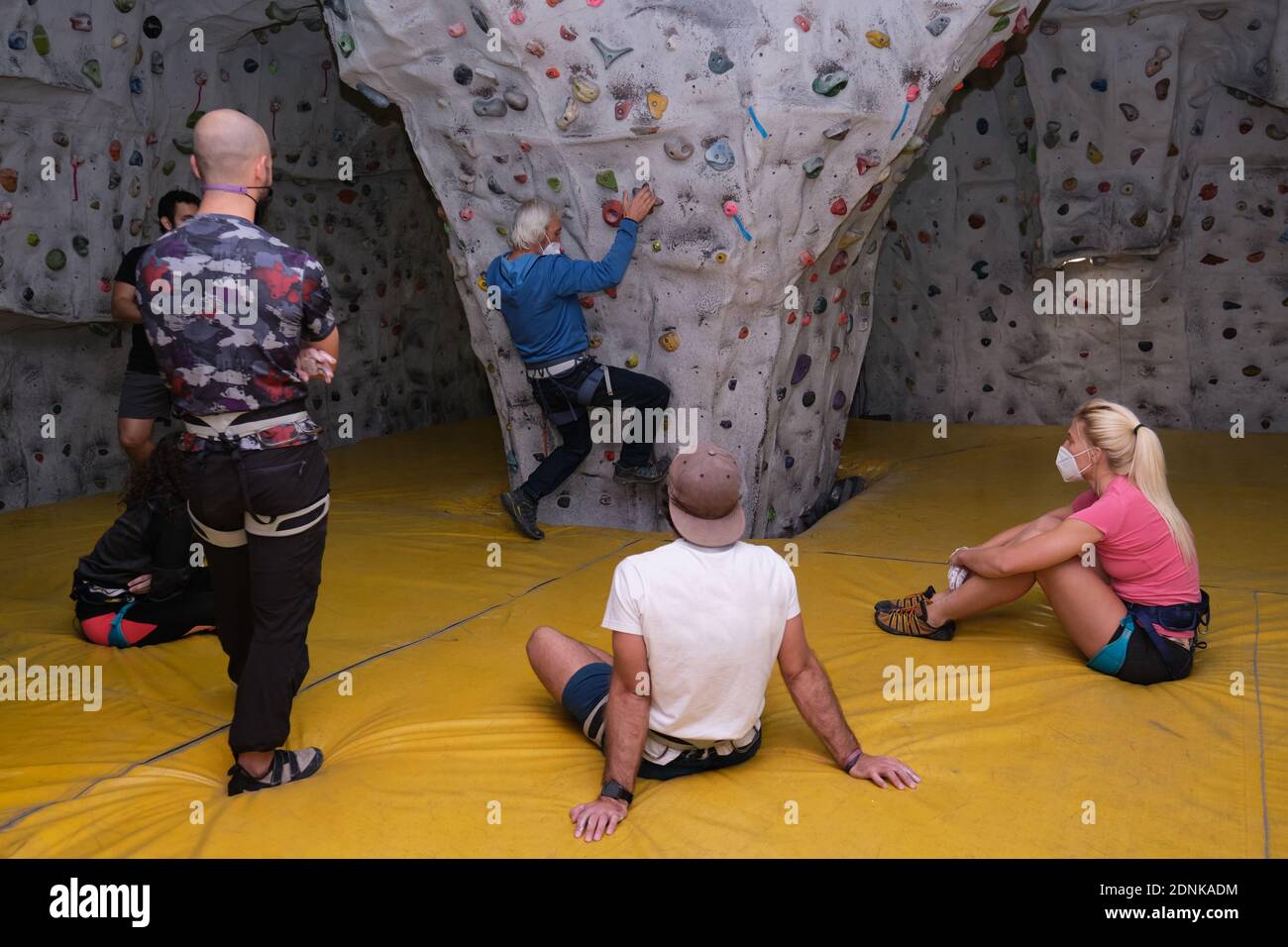 Climbing instructor wearing protective face mask showing how to climb a ...