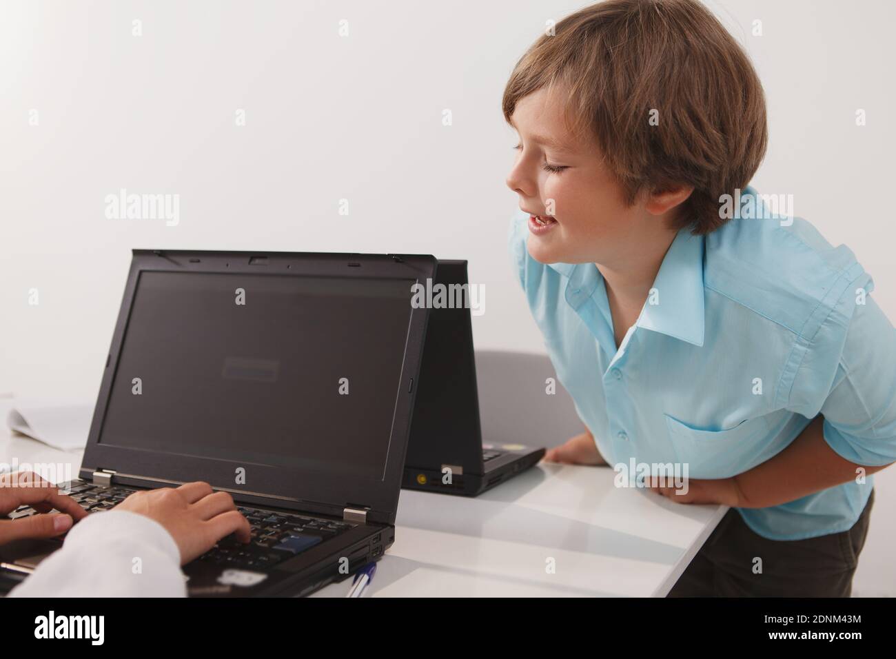 Adorable little boy looking at computer screen of his classmate during ...