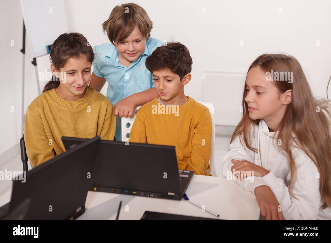 Group of kids working on a project together, using laptops in class ...