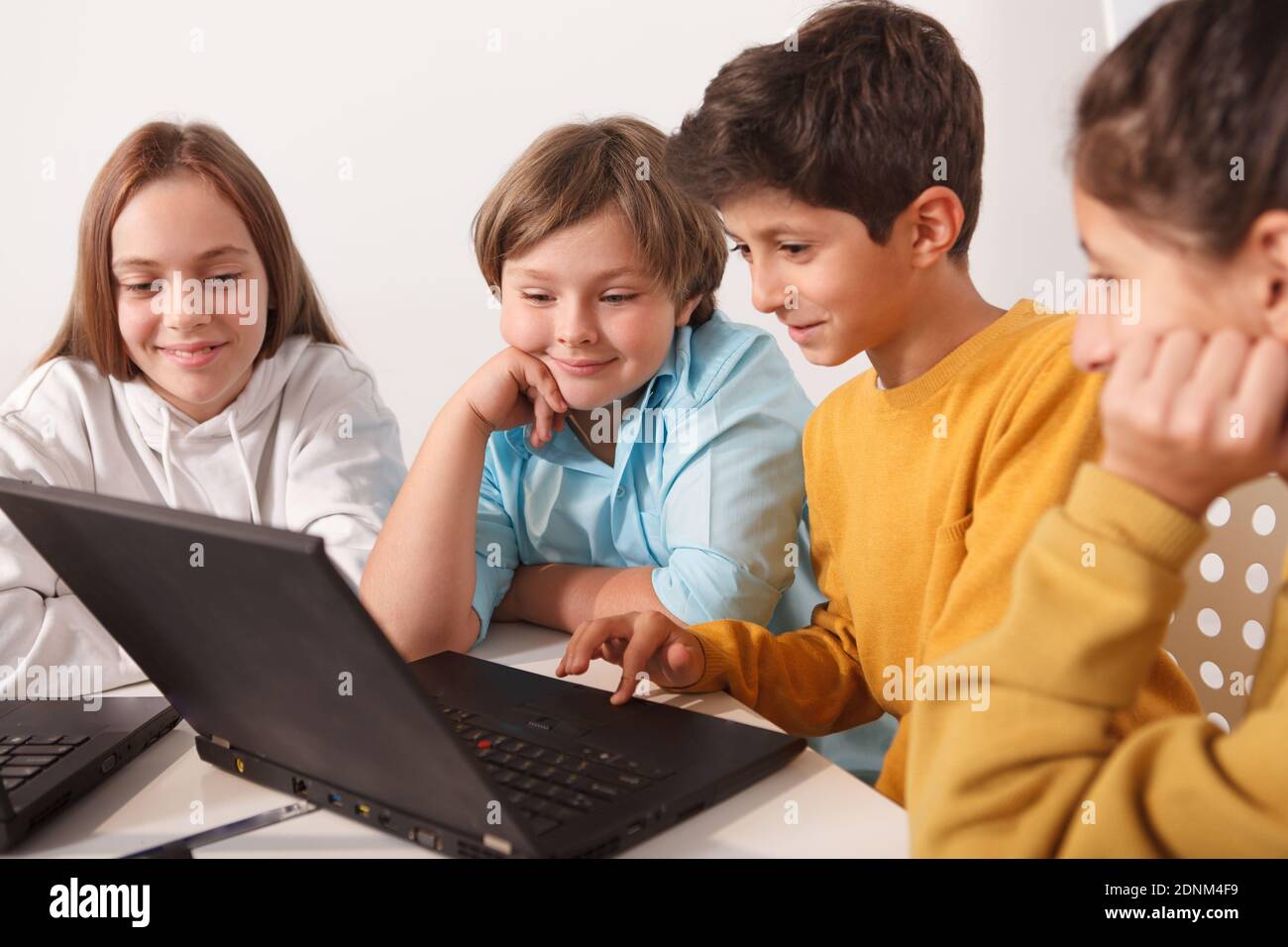 Cheerfu; kids enjoying working on a project together, using computer ...
