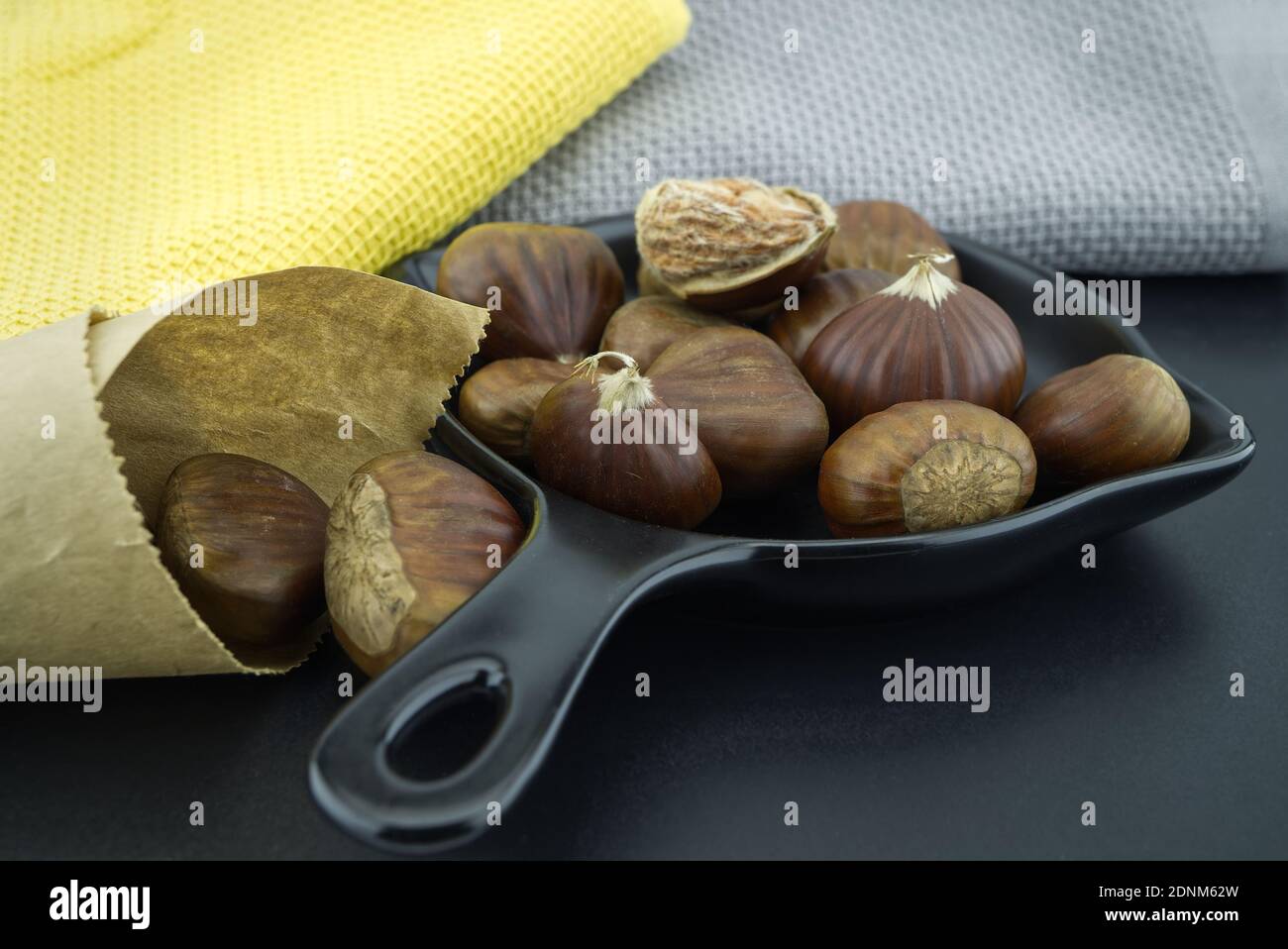 Fresh roasted chestnuts in their skins in a conical paper cone and ...
