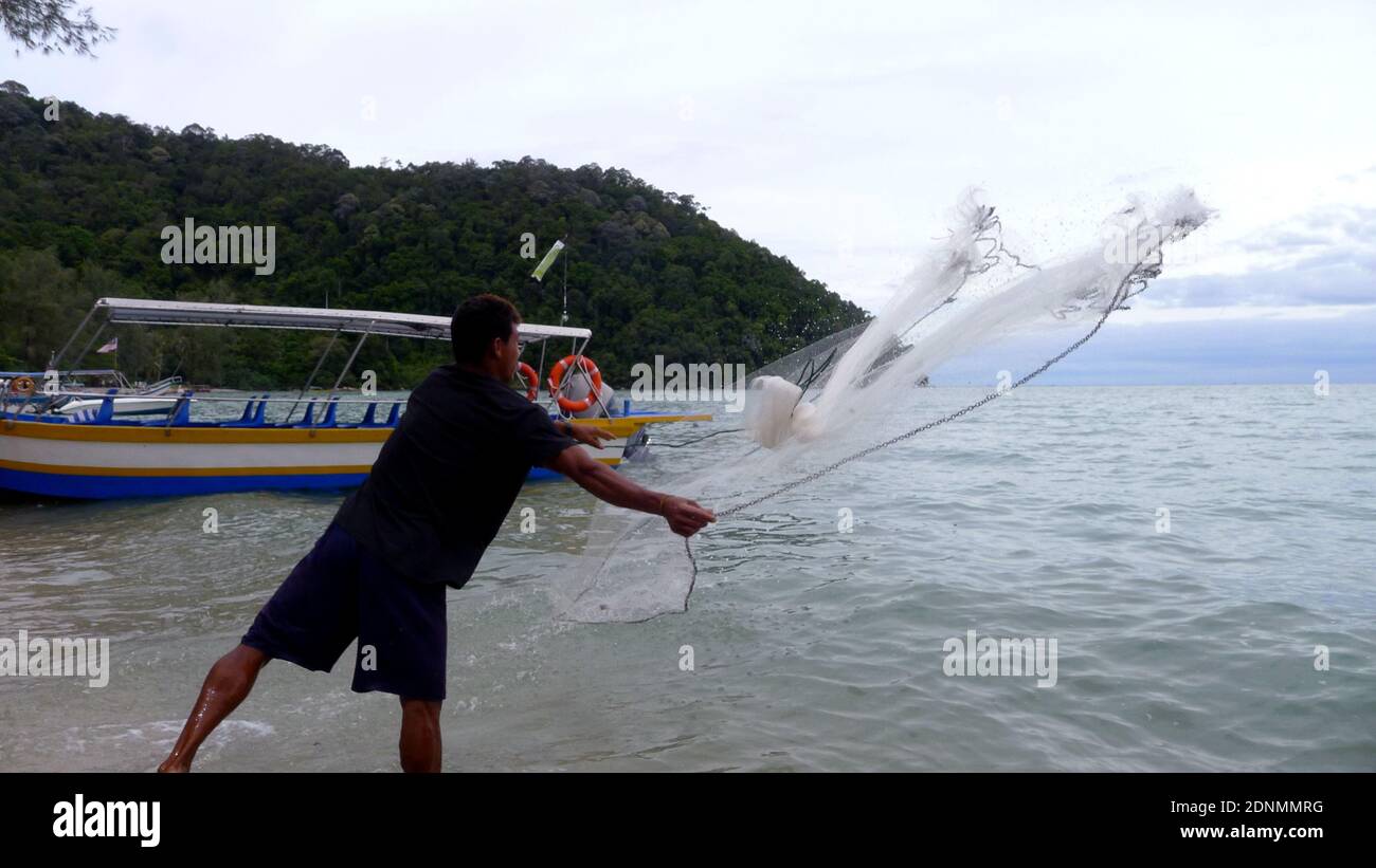 Fisher man throwing fishing net for catching fish for food Stock Photo ...