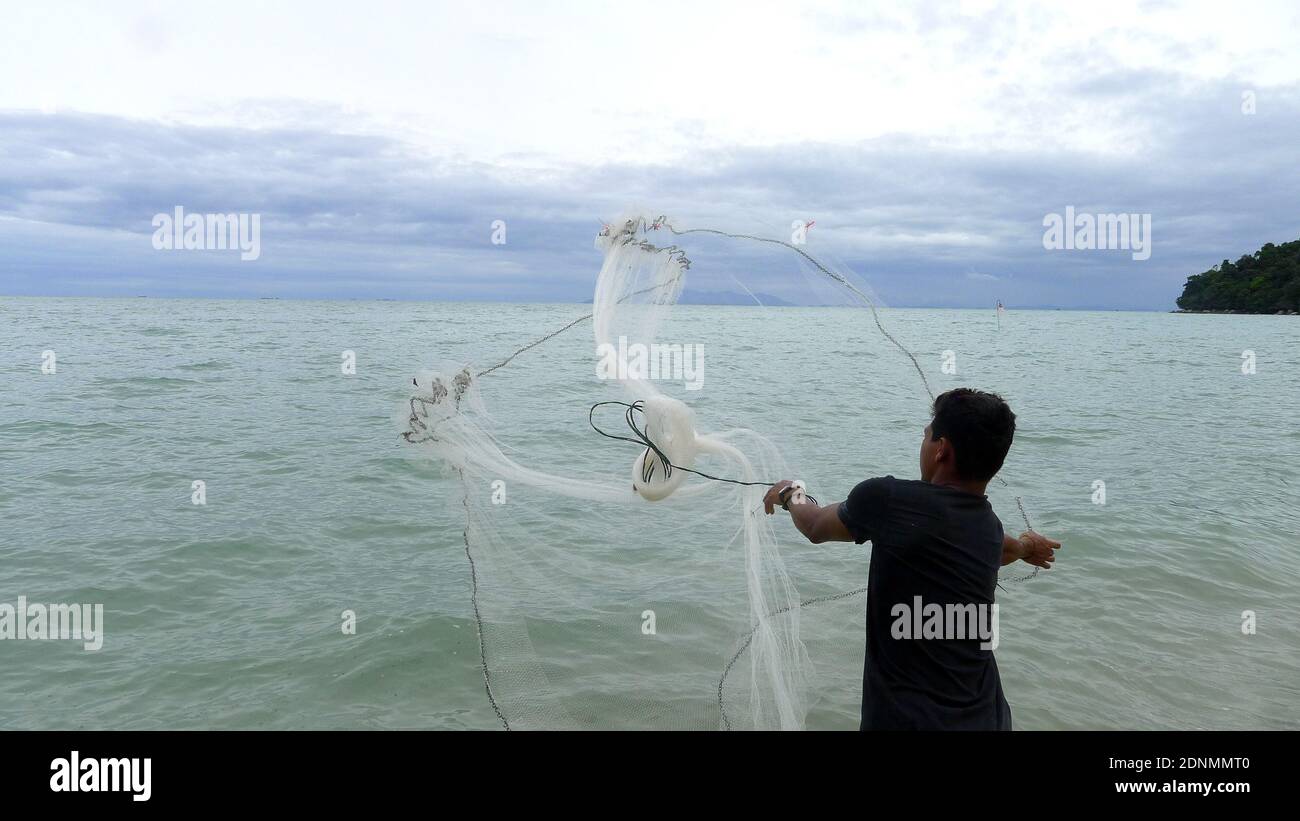 Fisher man throwing fishing net for catching fish for food Stock Photo ...