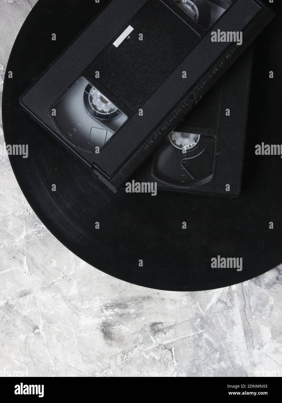 Retro vhs videocassettes from the 80s and vinyl records on a gray ...