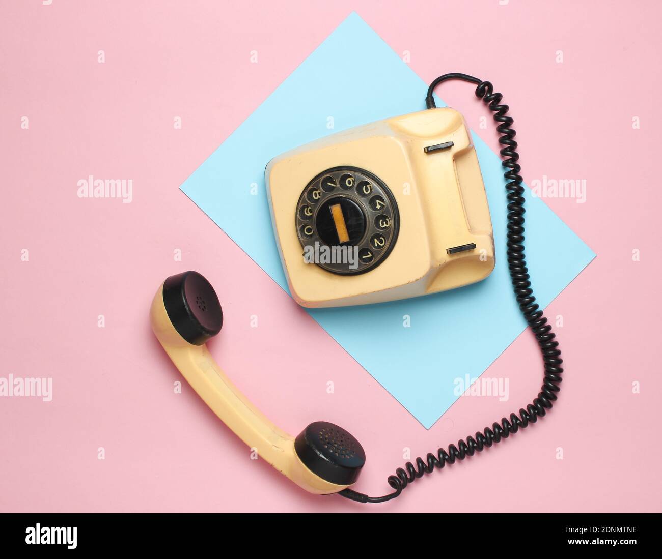 Retro rotary phone from 80s on a colored pastel background. Top view ...