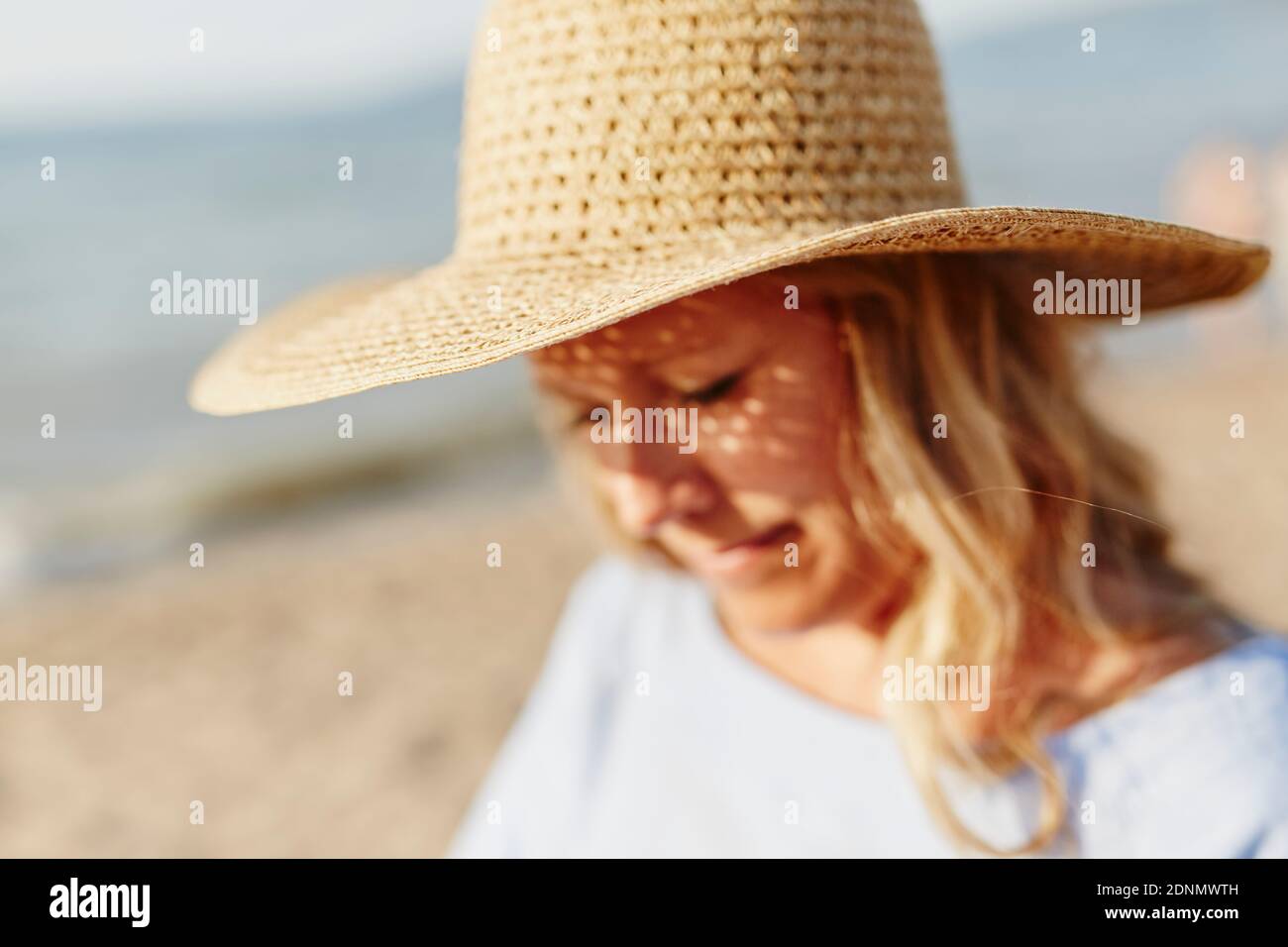 Woman wearing straw hat on beach Stock Photo - Alamy